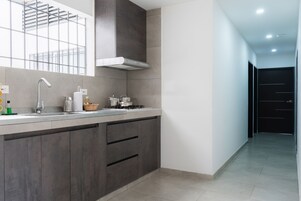 Cozinha moderna com uma janela ampla, fogão embutido e armário de madeira escura.