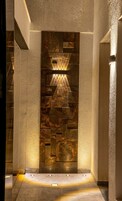 Interior moderno com parede de pedra e iluminação embutida.