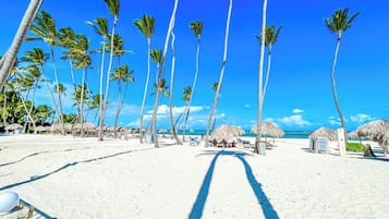 Uma praia com palmeiras e guarda-sóis de palha.