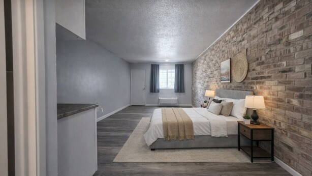 Quarto com cama, mesas de cabeceira, parede de tijolos e janela.