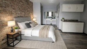 Um quarto com cama, mesas de cabeceira, um espelho e um guarda-roupa branco.