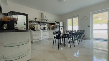 Uma cozinha moderna com área de jantar, destacando um piso de mármore, forno embutido e uma janela ampla que oferece luz natural.