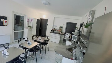 Cozinha moderna com área de refeições, equipada com geladeira, micro-ondas e cafeteira.