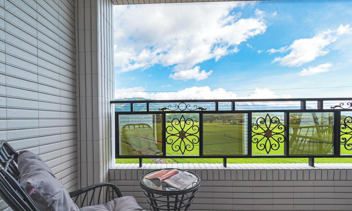 Varanda com vista para um campo verde e um céu limpo.