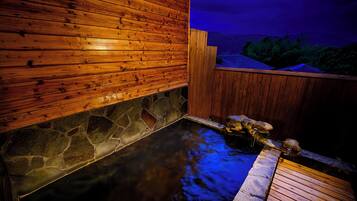 Um spa de madeira com parede de pedra, deck de madeira e vista para montanhas.