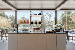 Um café moderno com uma vitrine de vidro repleta de doces e uma máquina de café.