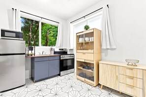 Uma cozinha moderna com geladeira, fogão, micro-ondas e um armário de madeira com portas de vidro.