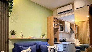 Quarto de hotel moderno com sofá, cama, cozinha compacta e banheiro.