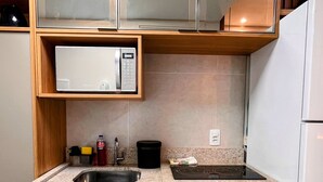 Uma cozinha compacta com micro-ondas integrado, pia e fogão.