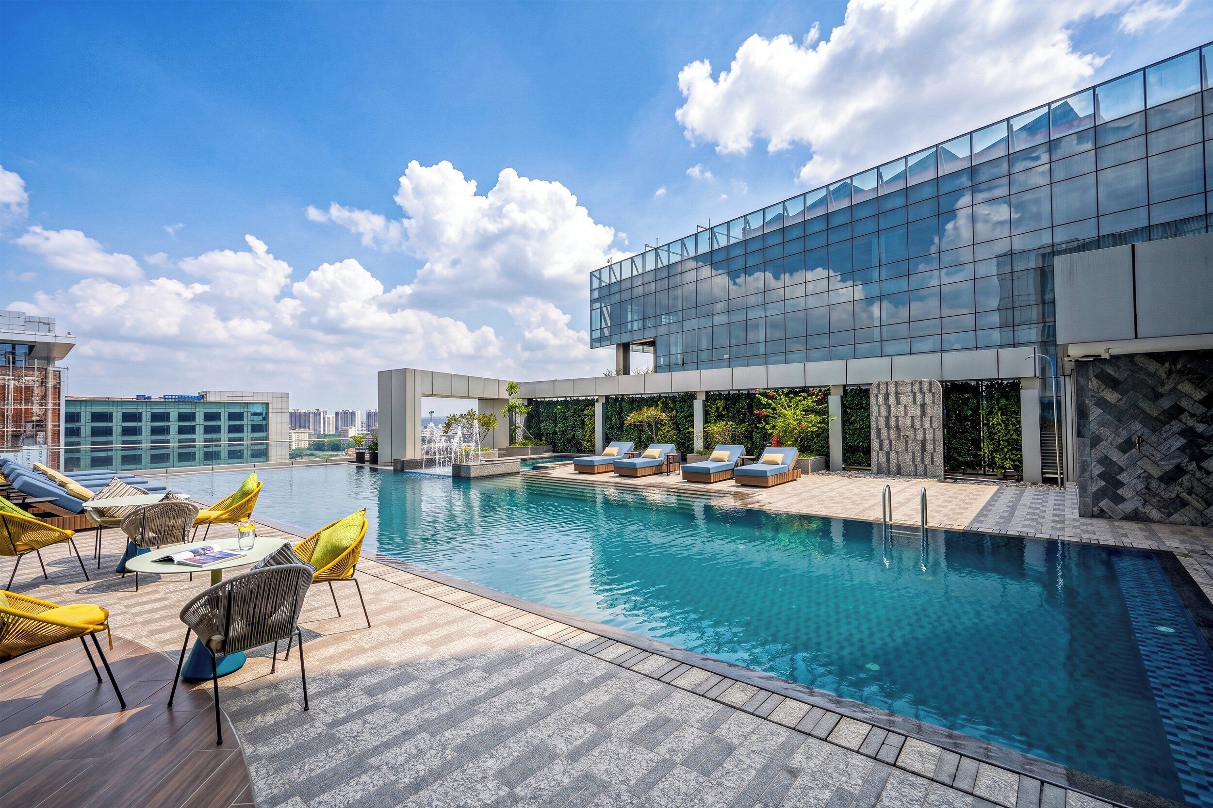 Piscina no terraço com espreguiçadeiras e um edifício moderno ao fundo.