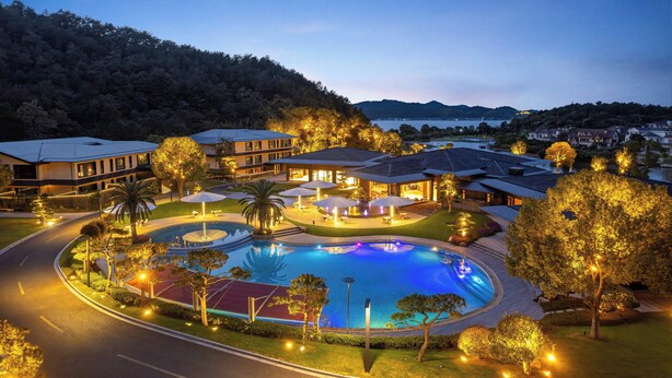 Um resort com piscina, vários edifícios e uma paisagem montanhosa ao fundo.