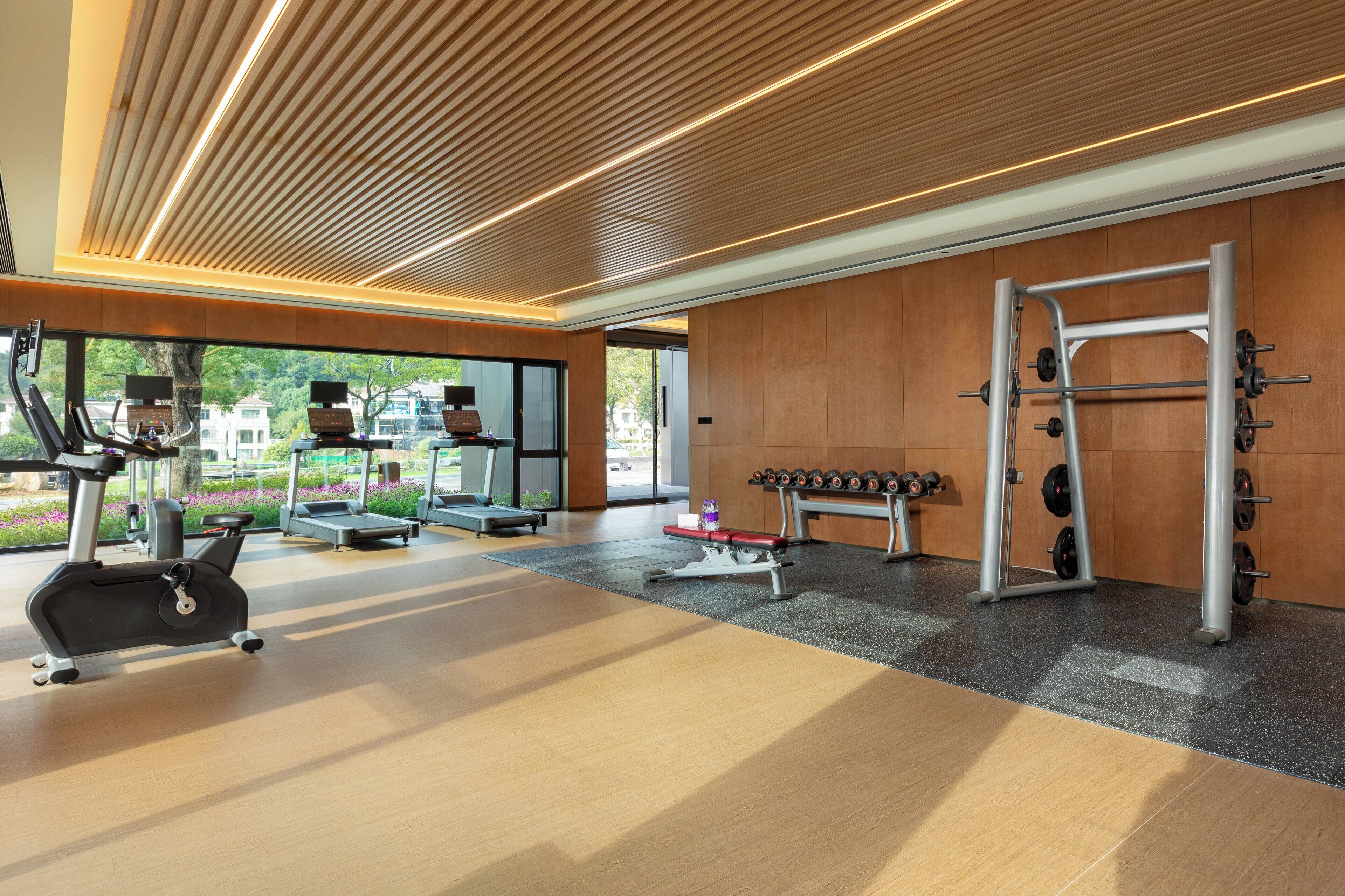 Academia moderna com equipamentos de cardio, pesos livres e barra para puxar.