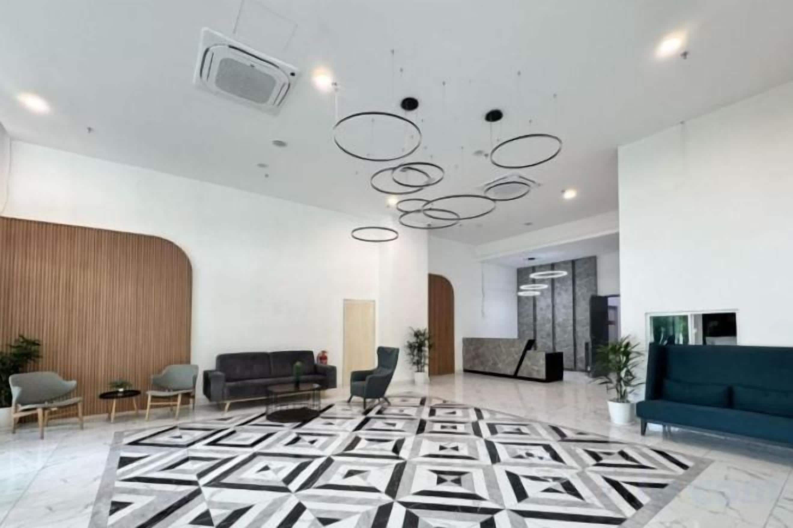 Um lobby moderno com piso de padrão geométrico, áreas de estar e balcão de recepção.