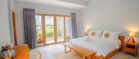 Um quarto espaçoso com uma cama grande, um banco de madeira e uma escrivaninha com uma cadeira.