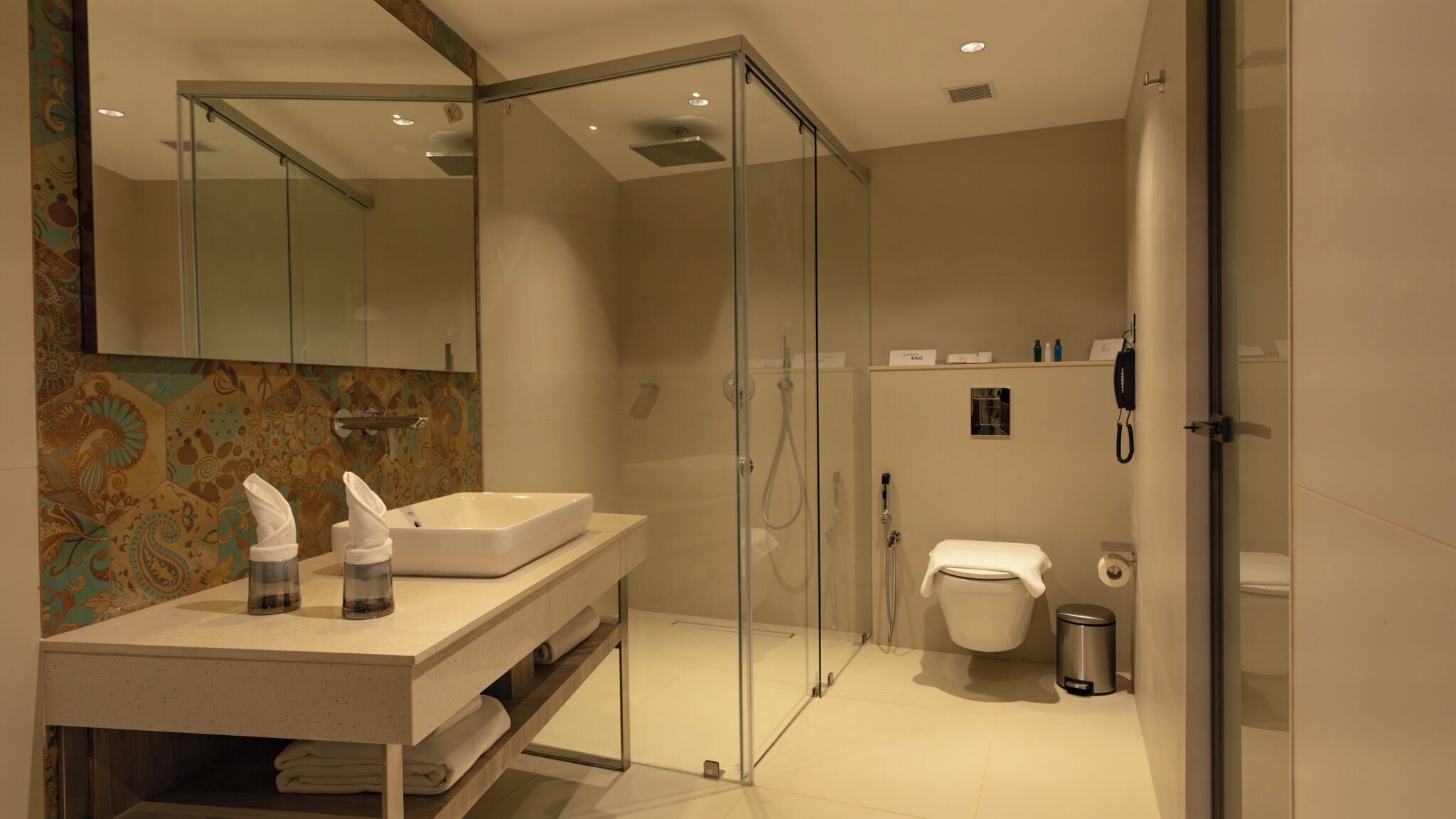 Casa de banho moderna com chuveiro em cabine de vidro, lavatório branco e sanita.