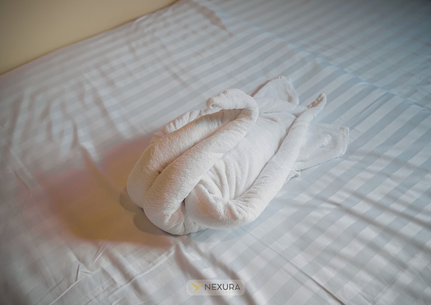 Toalha branca dobrada sobre uma cama com padrão xadrez.