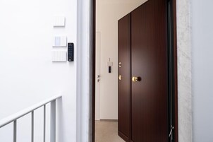 Um corredor com uma porta dupla, um interruptor de luz na parede e um controle remoto.