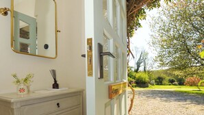 Uma porta com uma placa indicando 'Copper Mine Cottage', um espelho, um vaso com flores e uma cômoda de madeira com gavetas.