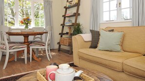 Uma sala de estar acolhedora com um sofá, uma mesa de madeira e uma estante escada.