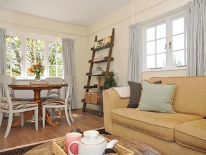 Uma sala de estar acolhedora com um sofá, uma mesa de madeira e uma estante escada.