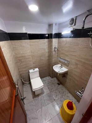 Uma casa de banho pequena com sanita, lavatório e chuveiro.