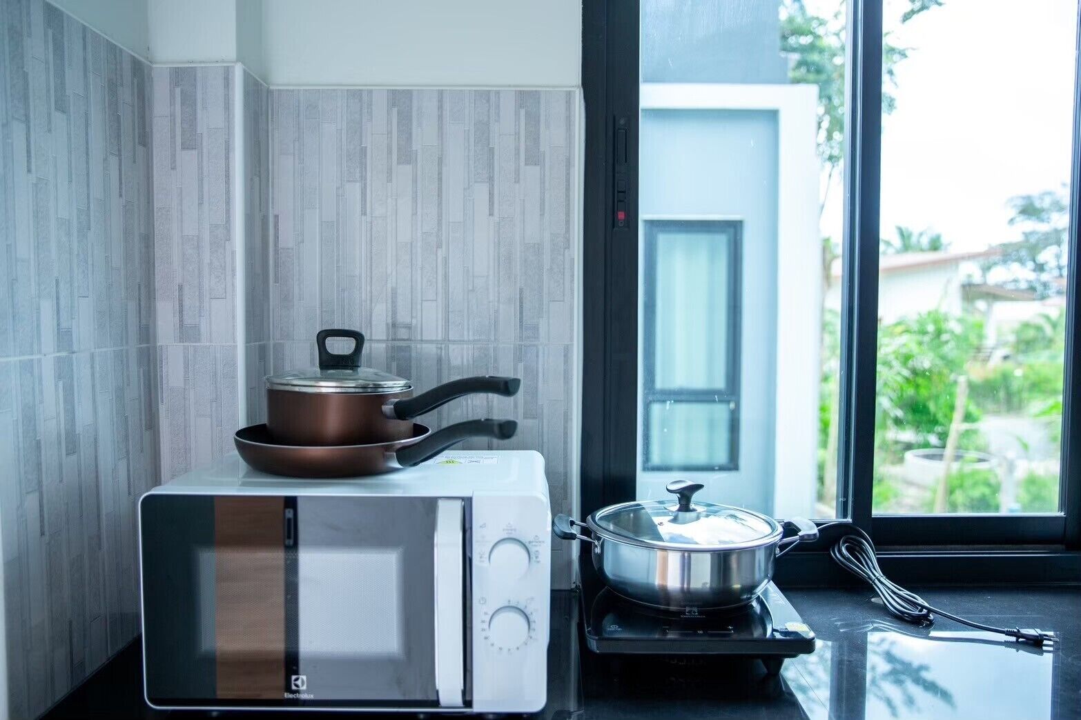 Uma cozinha compacta com micro-ondas, fogão e uma panela sobre o fogão.