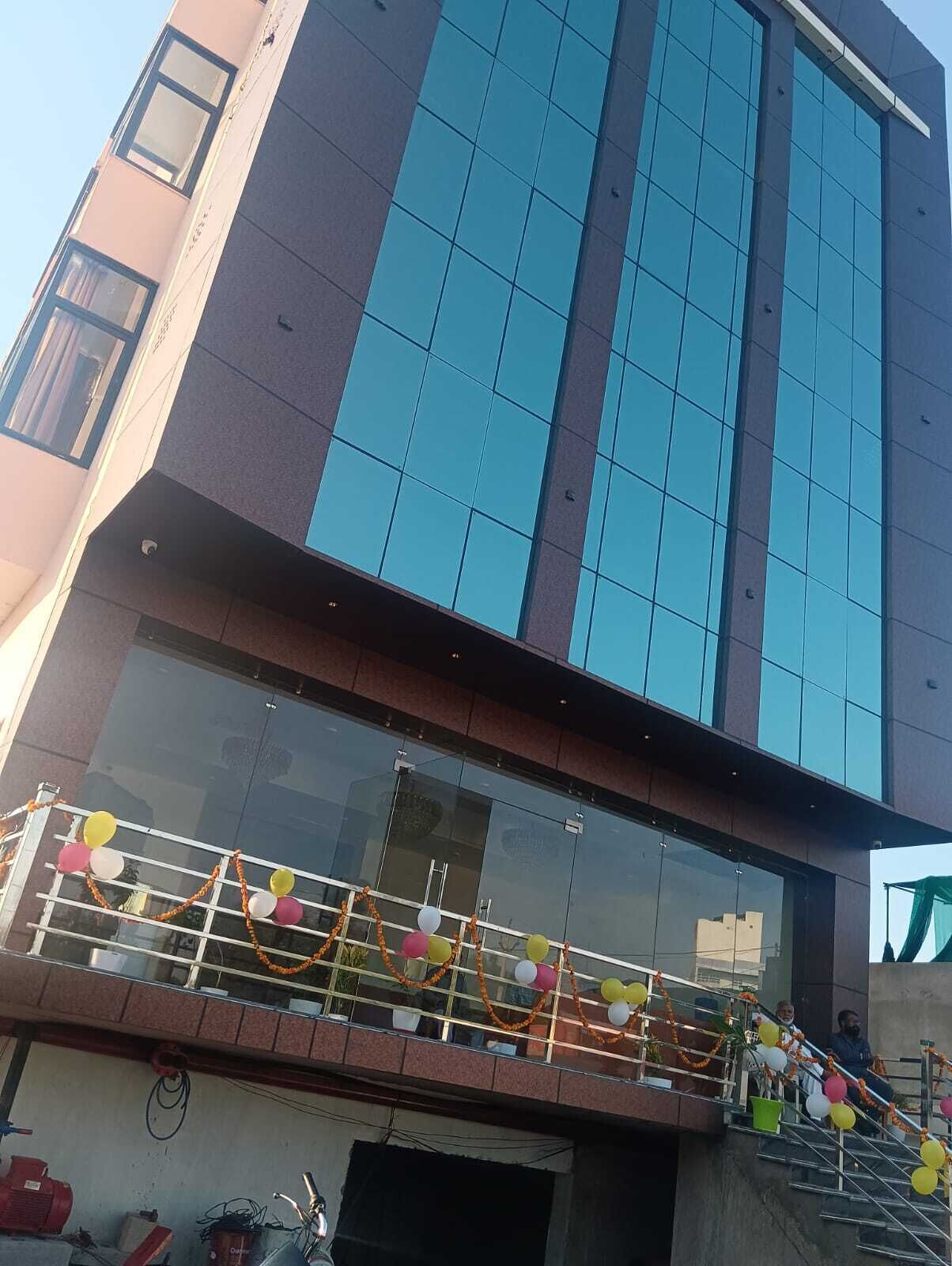 Um edifício moderno com fachada de vidro e varanda decorada com balões e guirlandas.