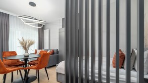 Quarto de hotel moderno com área de refeições, sofá e cama.