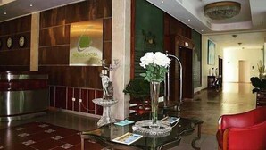 Um saguão de hotel com uma mesa de recepção, uma fonte e um vaso com flores.