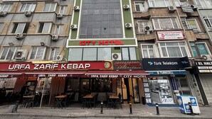 Um edifício de vários andares com um letreiro grande que diz 'CITY HOTEL' no topo.