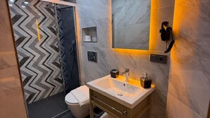 Um banheiro moderno com toucador de mármore, vaso sanitário e chuveiro.