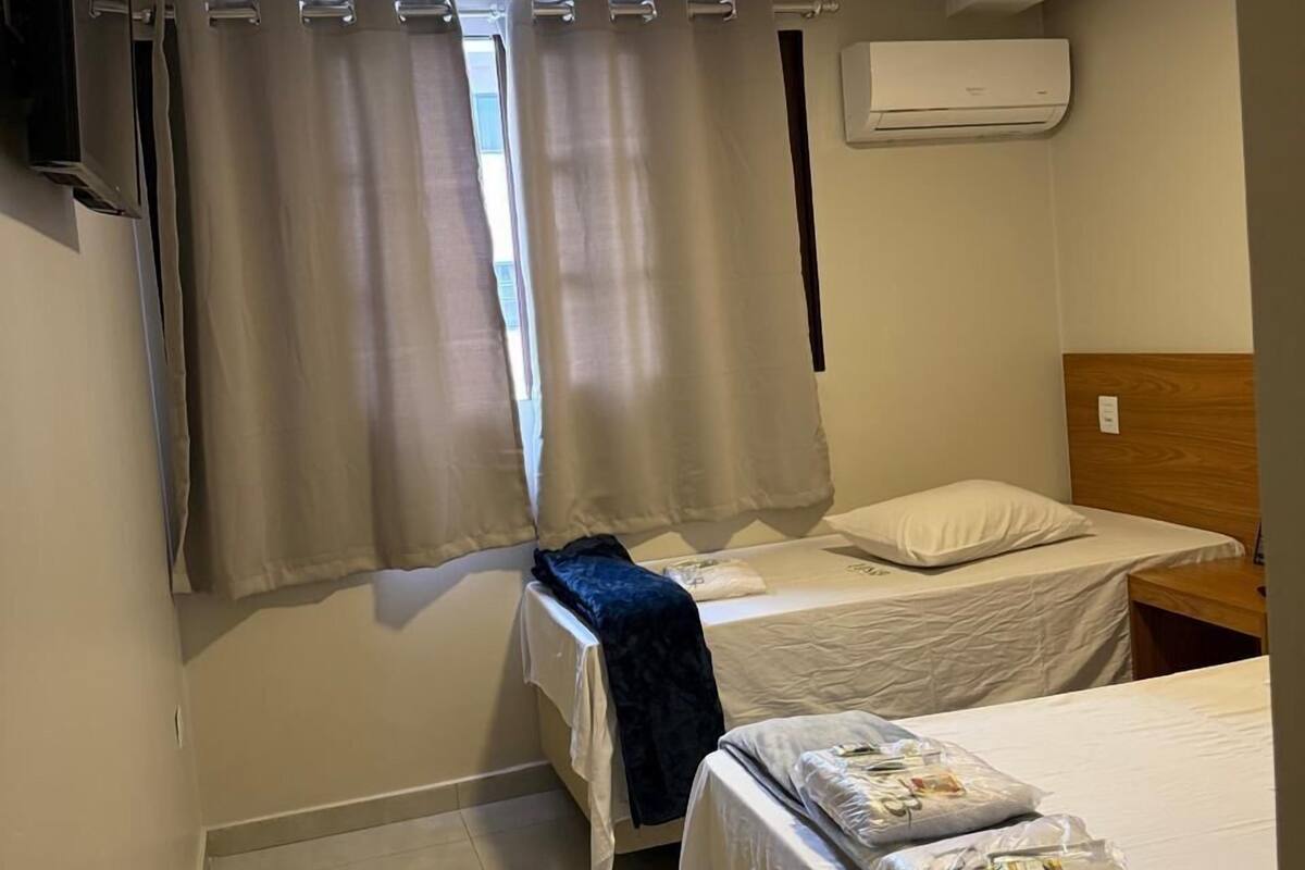 Quarto pequeno e limpo, com duas camas, televisão e ar condicionado.