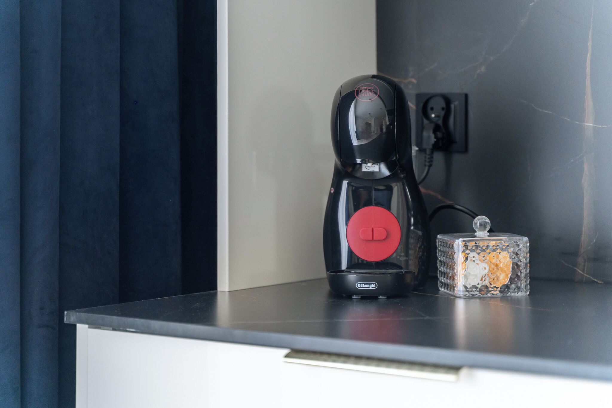 Uma cafeteira e um recipiente decorativo em uma bancada.