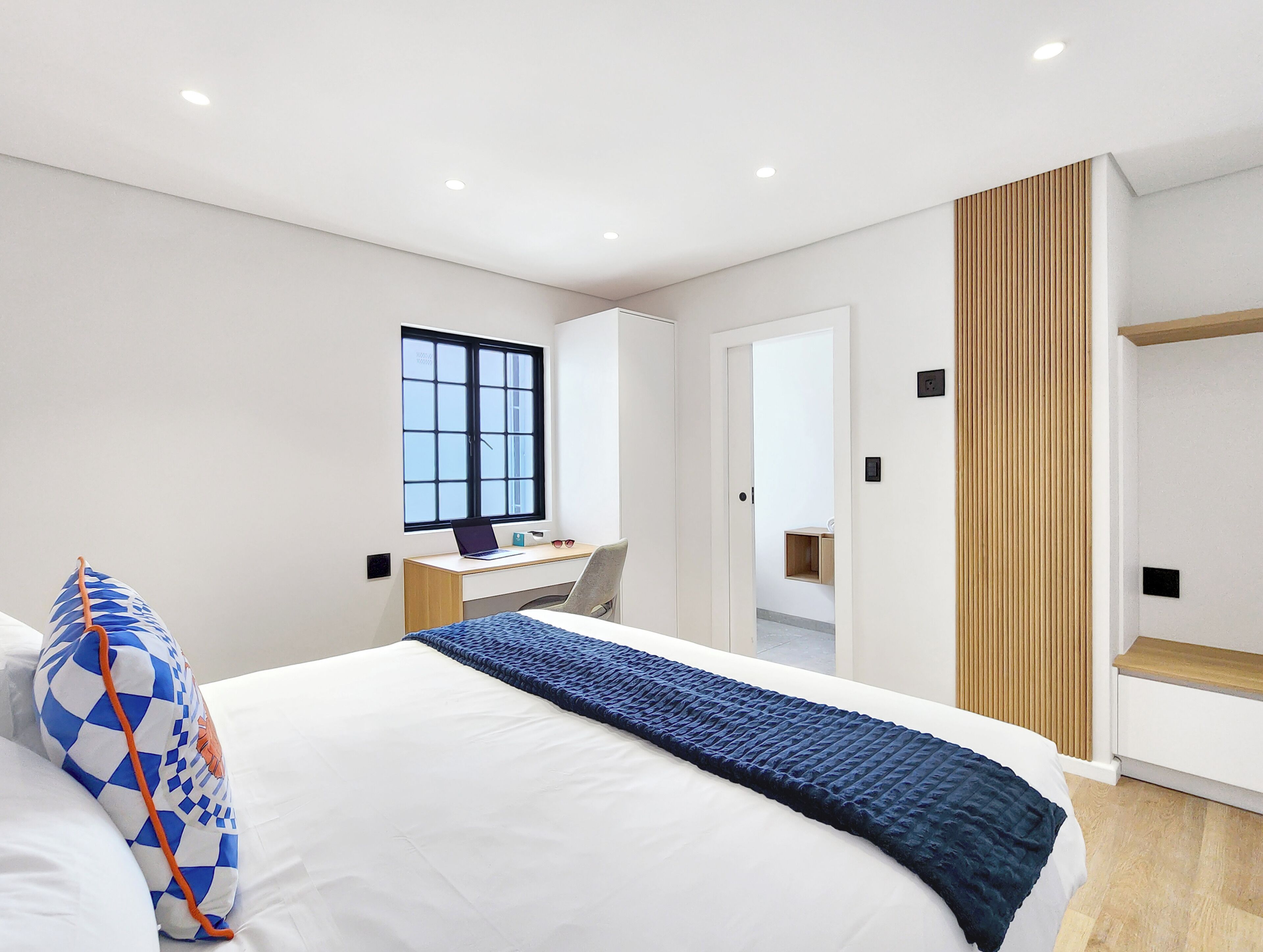 Quarto moderno com uma cama grande, uma escrivaninha e um computador.