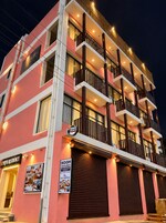 Um hotel de vários andares com varandas, um aviso indicando quartos disponíveis e uma entrada visível.