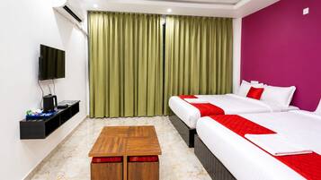 Quarto de hotel com cama, televisão, cafeteira e mesa de madeira.