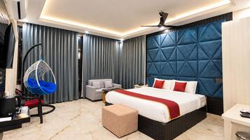 Quarto de hotel moderno com uma cama grande, uma cadeira suspensa, um sofá, uma escrivaninha e um ventilador de teto.