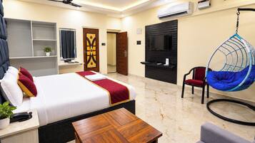 Quarto de hotel com cama, escrivaninha, cadeira suspensa, televisão e ar condicionado.