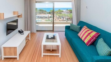 Uma sala de estar moderna com um sofá verde-água, uma mesa de centro branca e uma televisão fixada na parede.