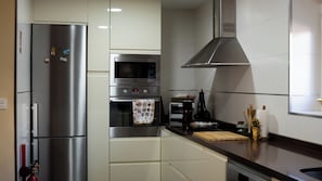 Uma cozinha moderna com eletrodomésticos de aço inoxidável, forno embutido e coifa.