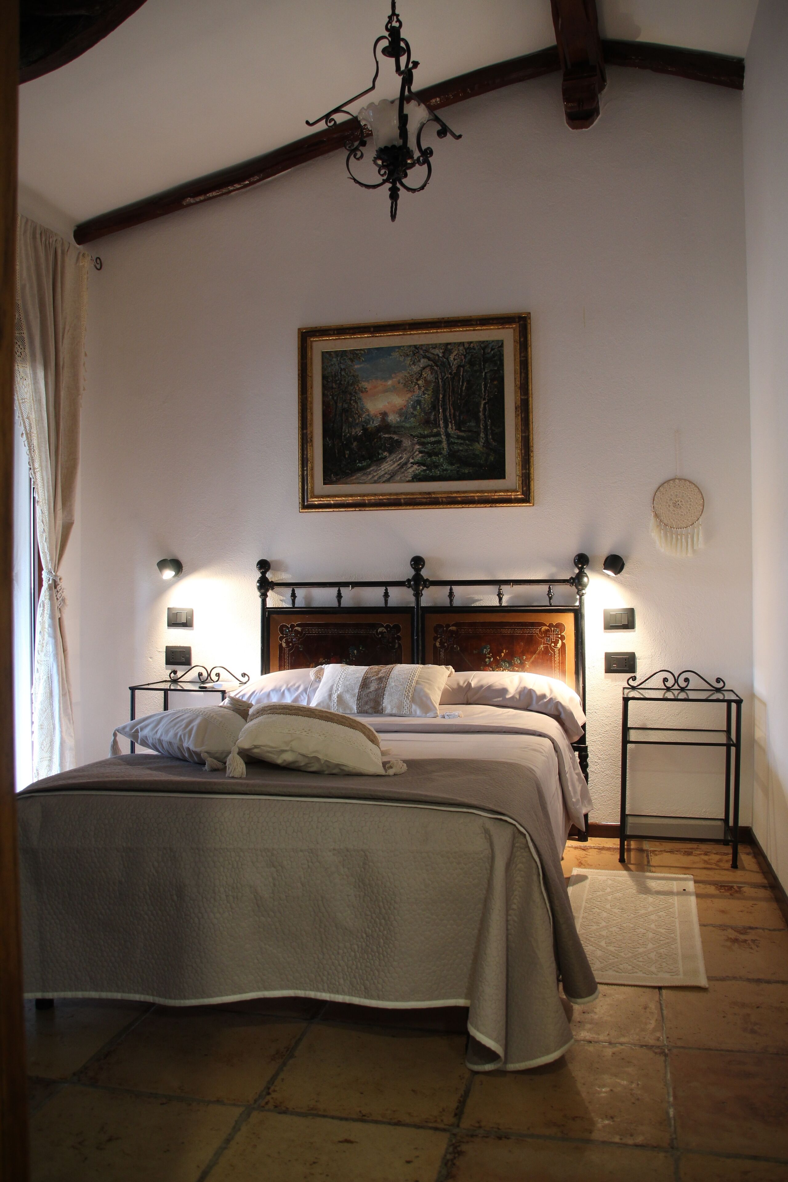 Um quarto com cama, um quadro, um candelabro e uma mesa de cabeceira.
