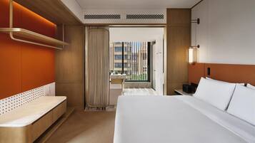Quarto de hotel com cama, mesa de cabeceira e vista para uma varanda.