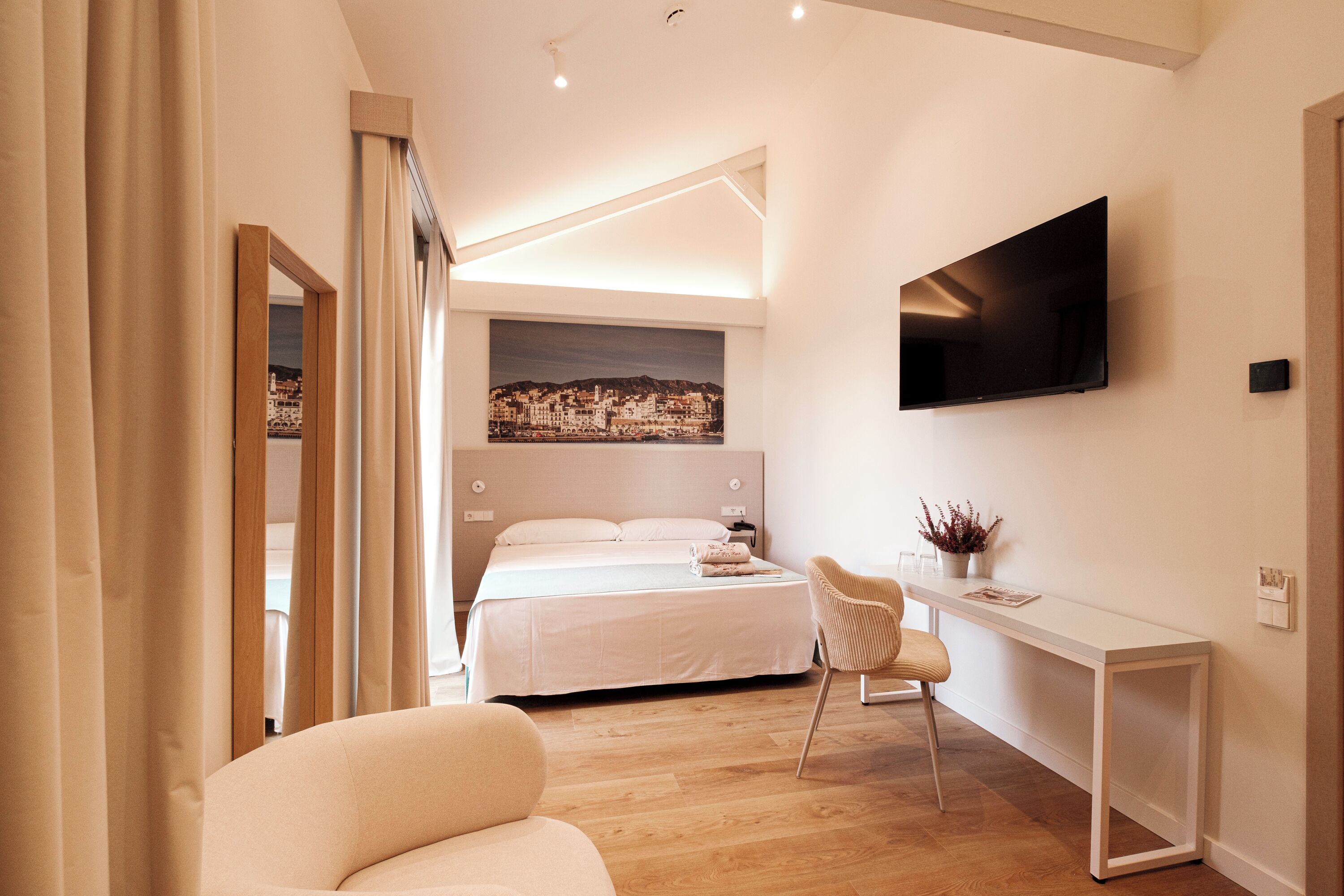 Um quarto moderno com cama, escrivaninha, cadeira, televisão e um quadro na parede.