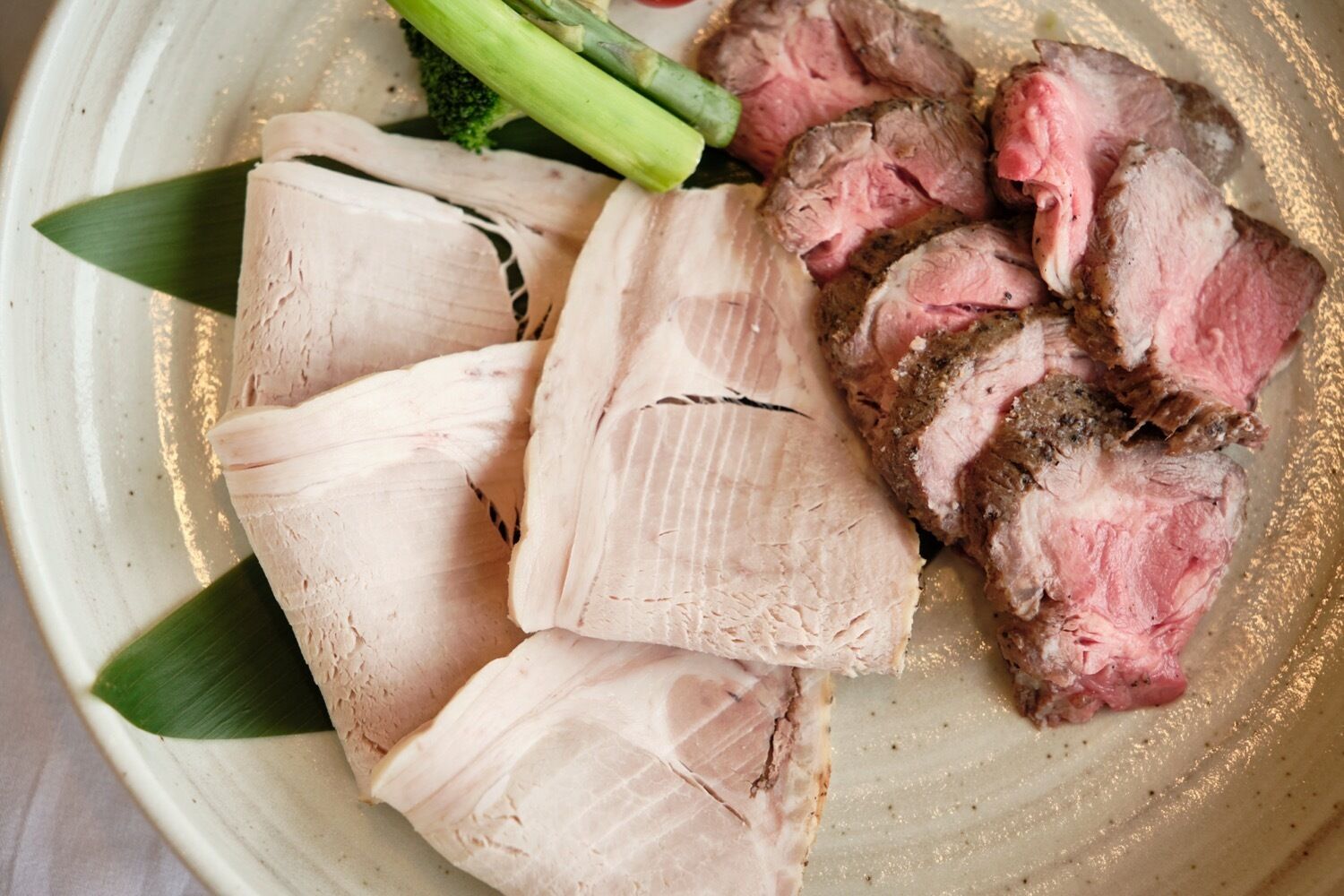 Um prato com carne fatiada e legumes.