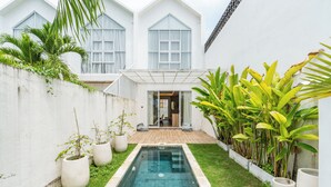 Uma casa moderna com piscina, deck de madeira e plantas em vasos.