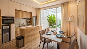 Cozinha moderna com armários de madeira, eletrodomésticos de aço inoxidável e área de refeições com mesa posta para quatro pessoas.