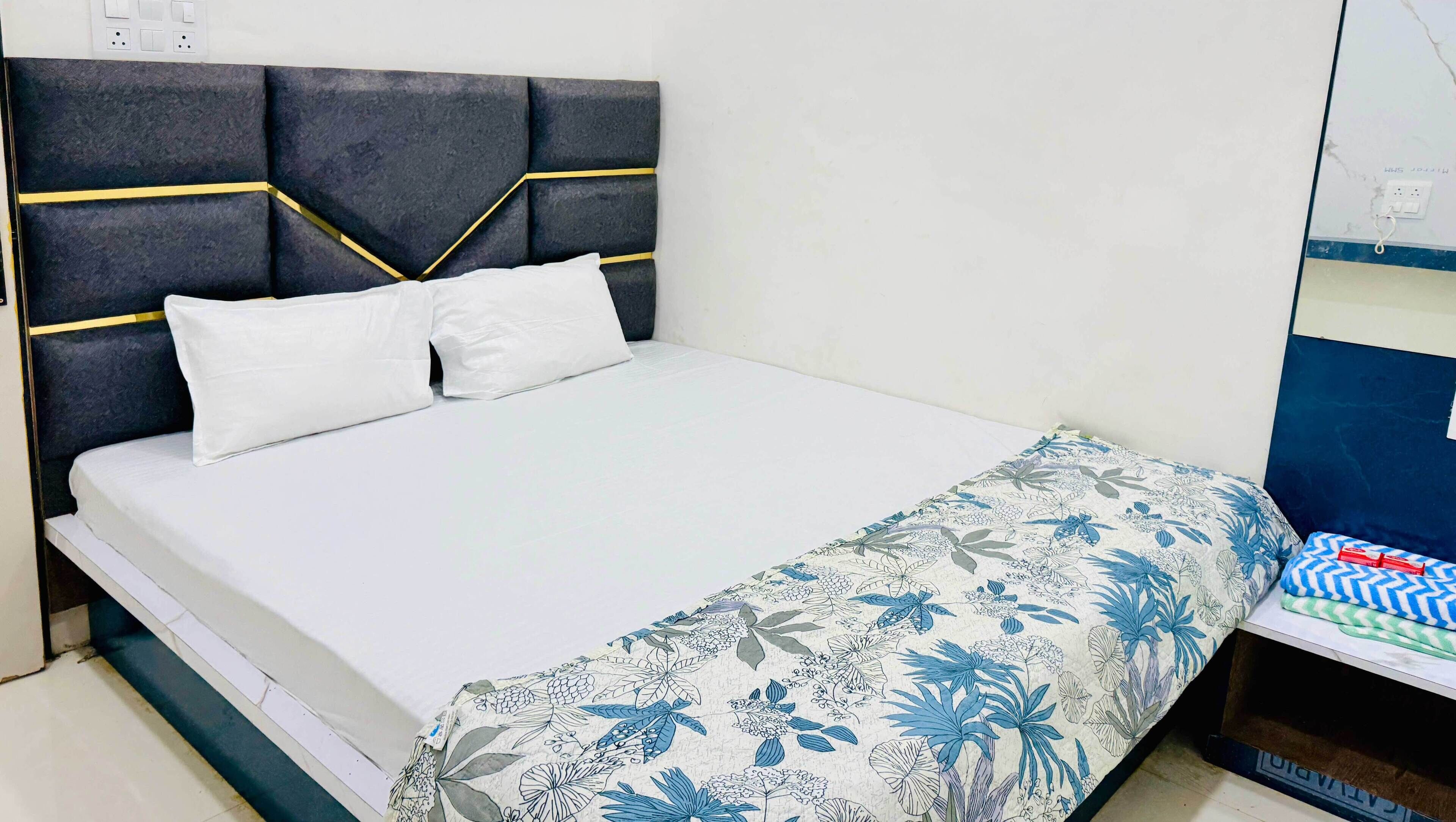 Uma cama com colchão branco e colcha estampada.