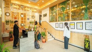 Uma área de recepção com escada de madeira, balcão de atendimento e parede com cartazes informativos emoldurados.
