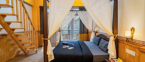 Quarto com cama de dossel, piso de madeira, escada e vista por grandes janelas.