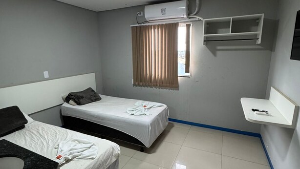 Quarto com duas camas, banheiro e pequena área de trabalho.